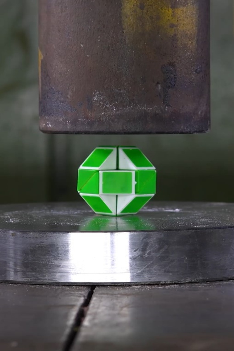 Rubik-Schlange unter hydraulischer Presse zerquetschen