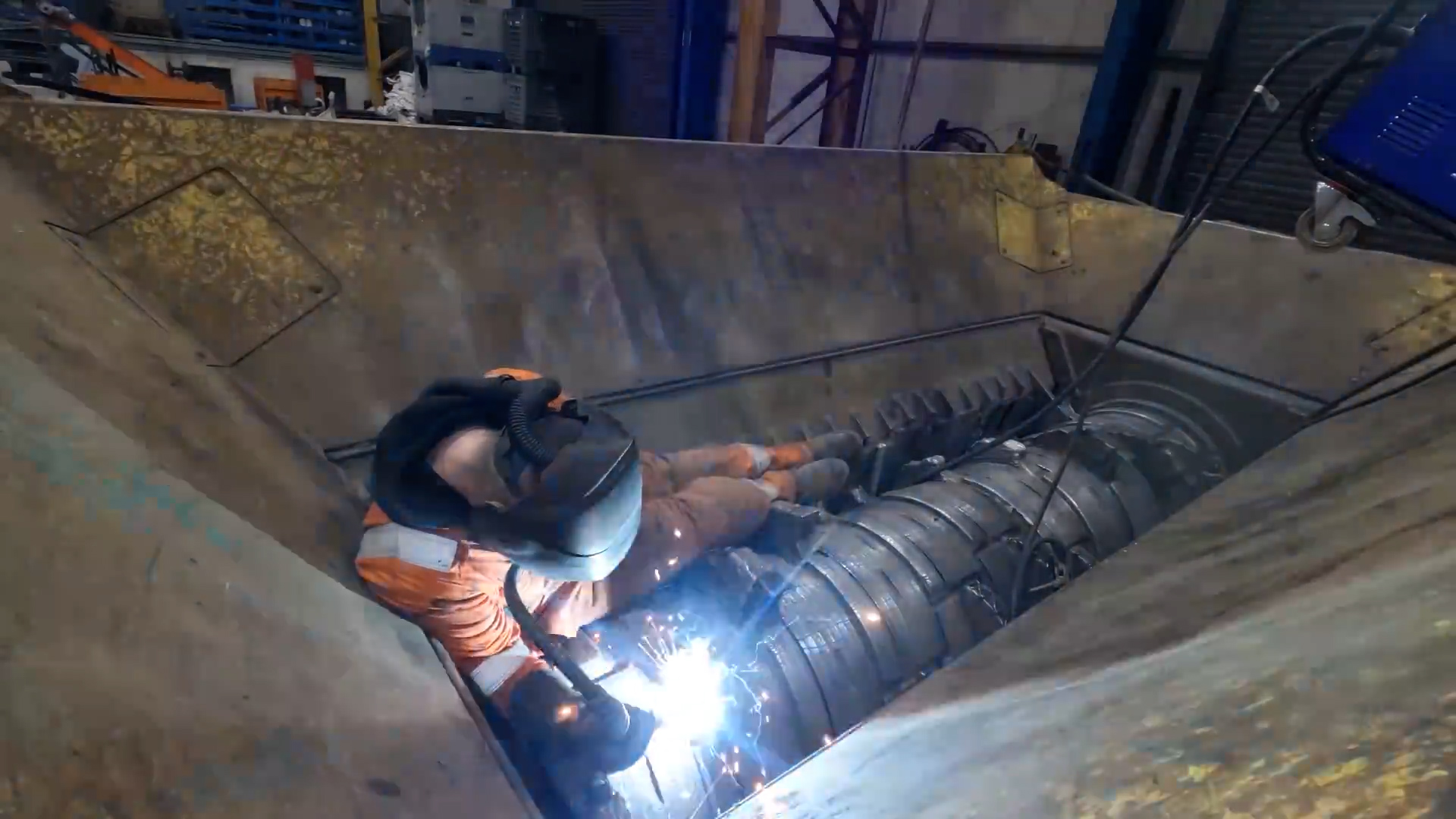 Welder repairing industrial shredder rotor inside heavy-duty recycling ...