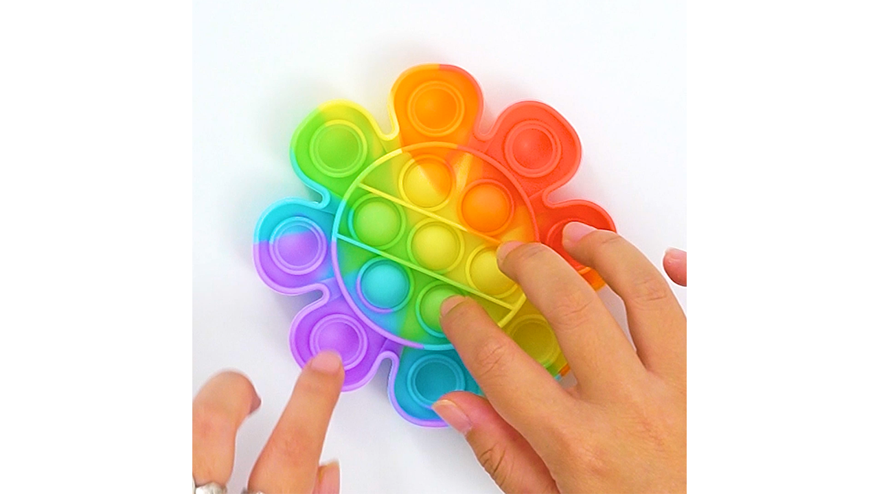 Playing with a colorful flower shaped pop it in bright rainbow colors