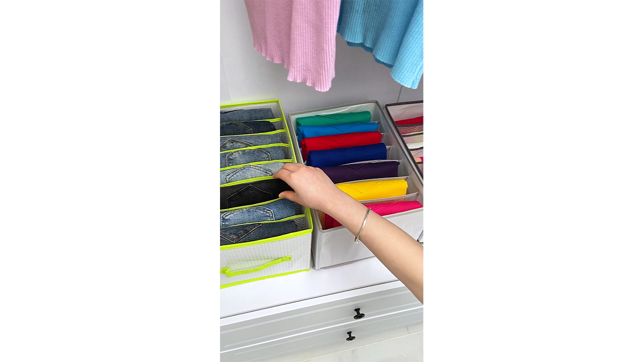 Organizing folded clothes in multi compartment storage box resulting in ...