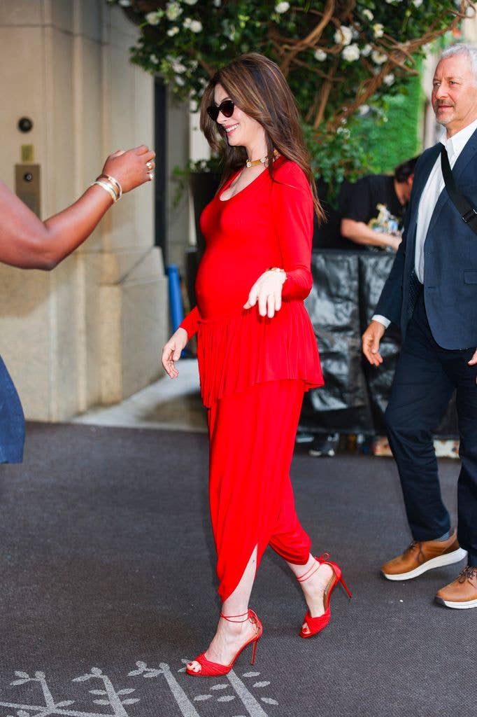 Anne Hathaway shows off blossoming baby bump in bold red look