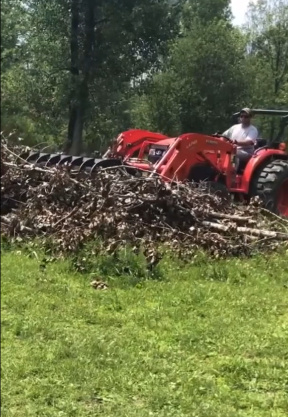 Tractor grapple handling a huge brush pile: Heavy cleanup in action