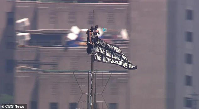 Daredevils scale Empire State Building and unfurl protest banner before ...
