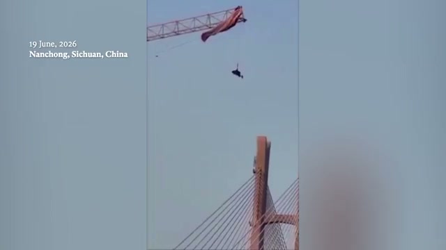 Paraglider dangles from crane after becoming snagged during jump