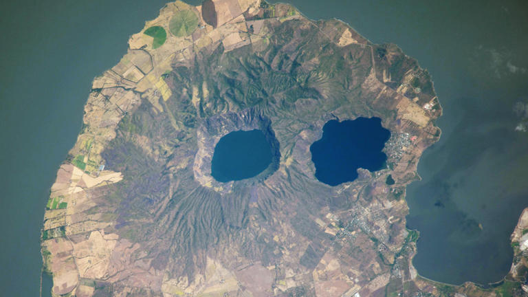 Shadowy tendrils of ancient lava have scarred a dark volcano in the ...