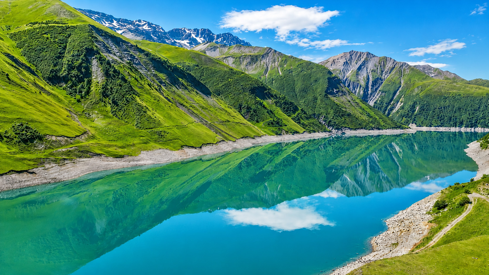 A mirror-like alpine lake reflecting green mountain slopes