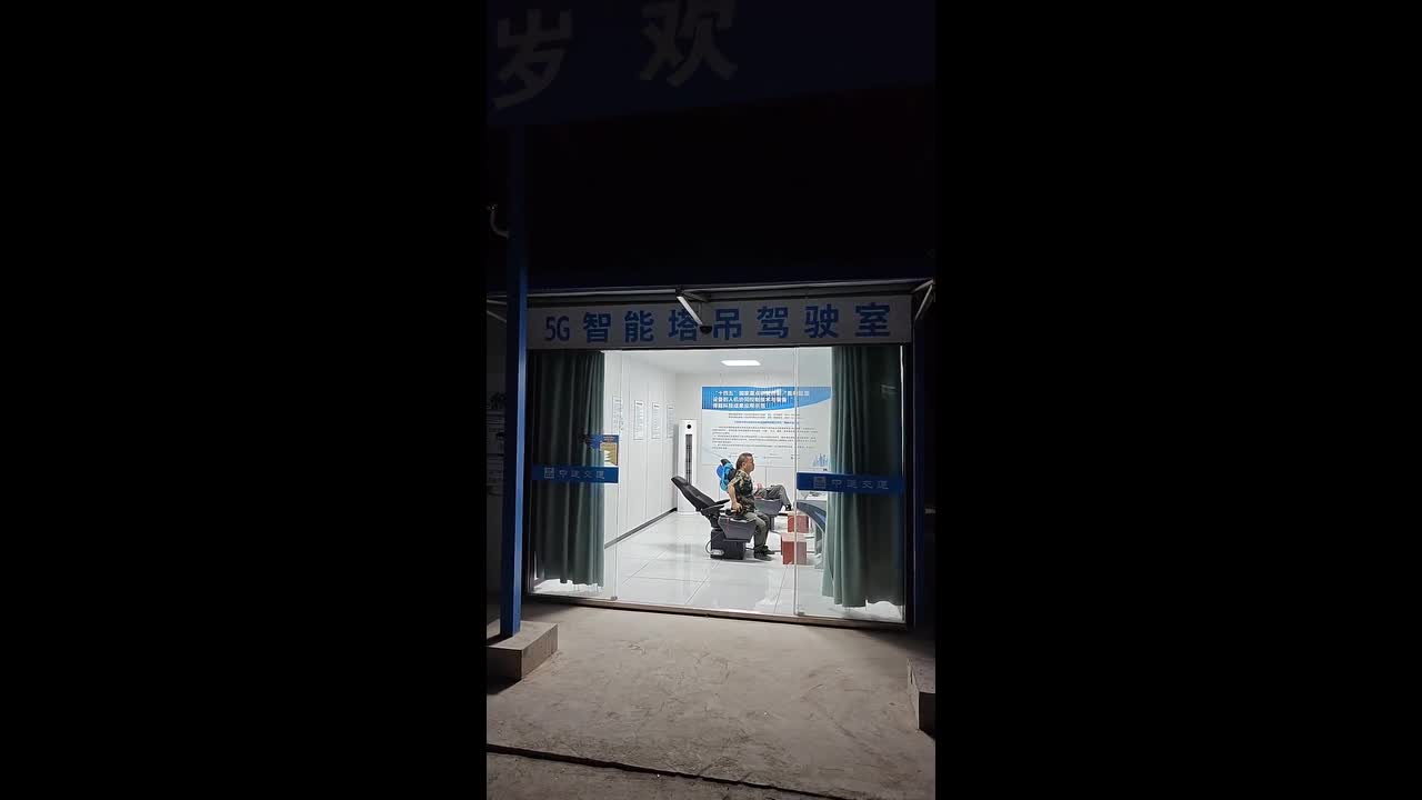 Workers control crane remotely from inside building at a yard in China