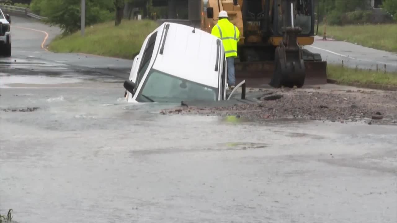 Driver rescued after car falls into water-filled sinkhole in downtown ...
