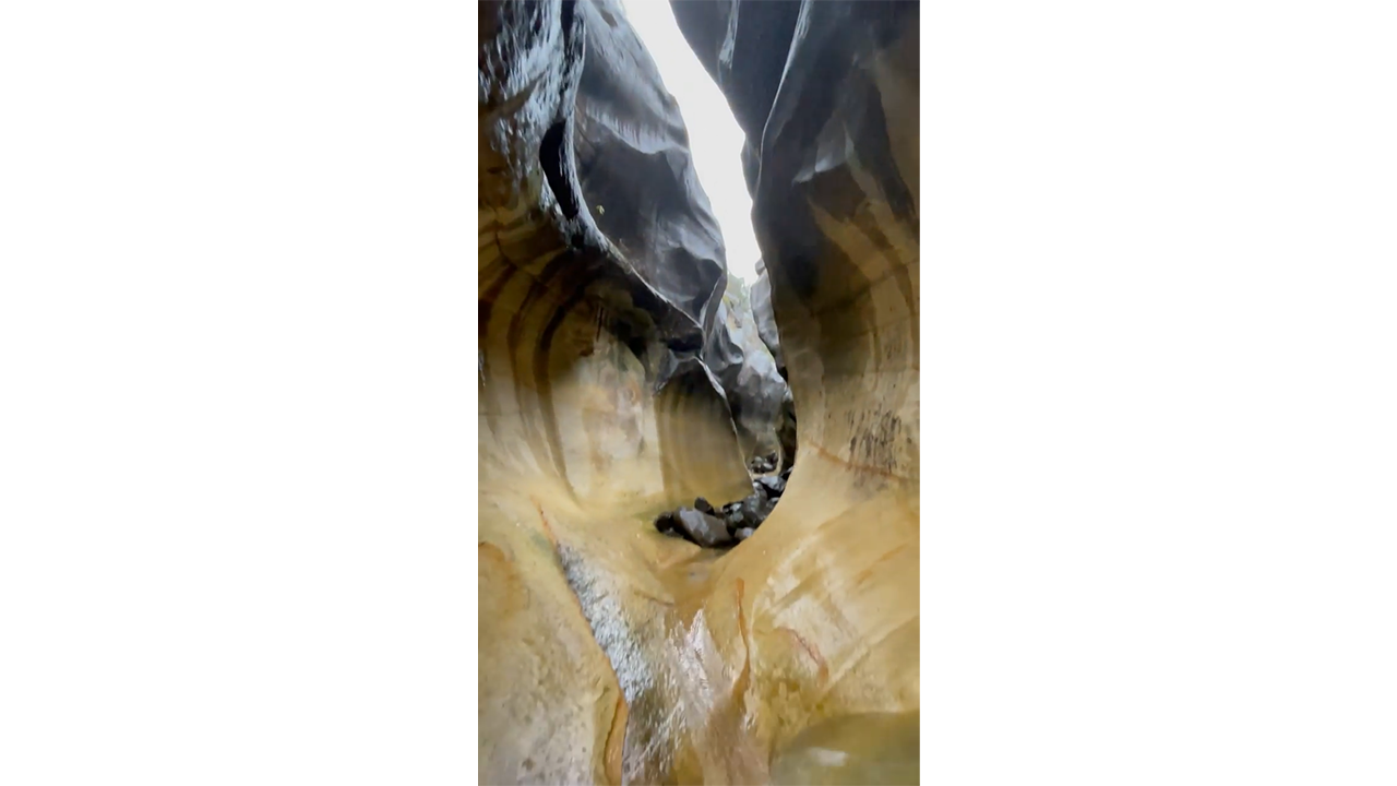 Exploring smooth sandstone canyon with flowing water through narrow ...