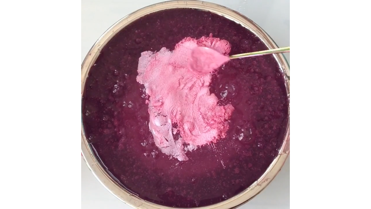 Mixing pink powder into dark purple slime creating vibrant berry swirl ...