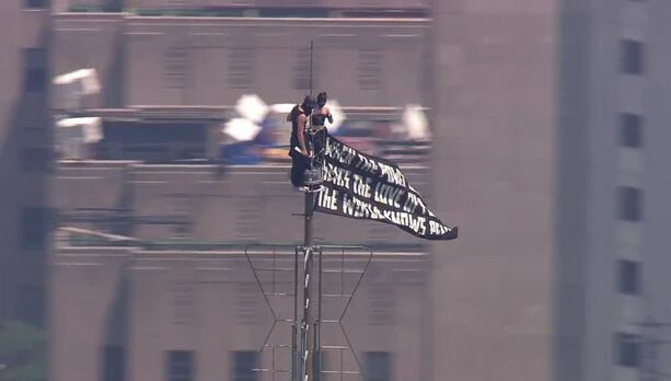 2 people climb to top of NYC’s Empire State Building, fly banner