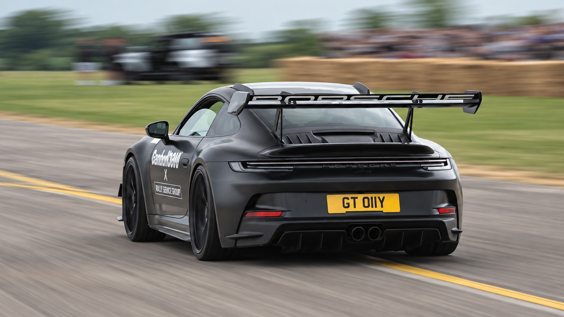 Porsche 911 Gt3 Sprints Past A Crowd With Its Wing Standing Tall