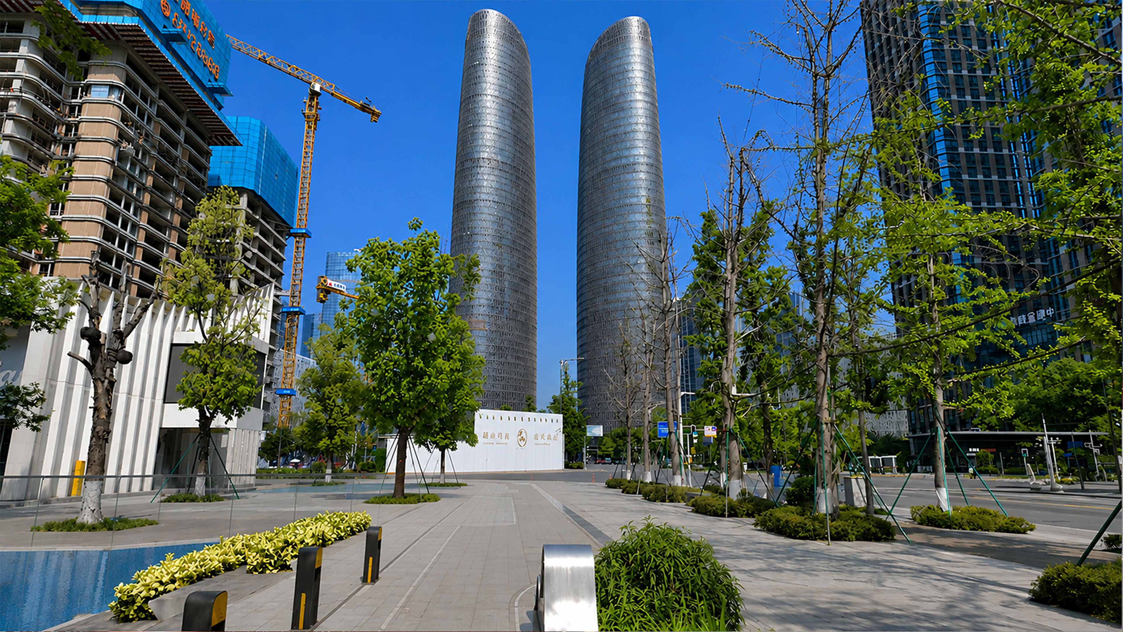 Chengdu’s curved twin towers stand beyond a tree-lined urban plaza