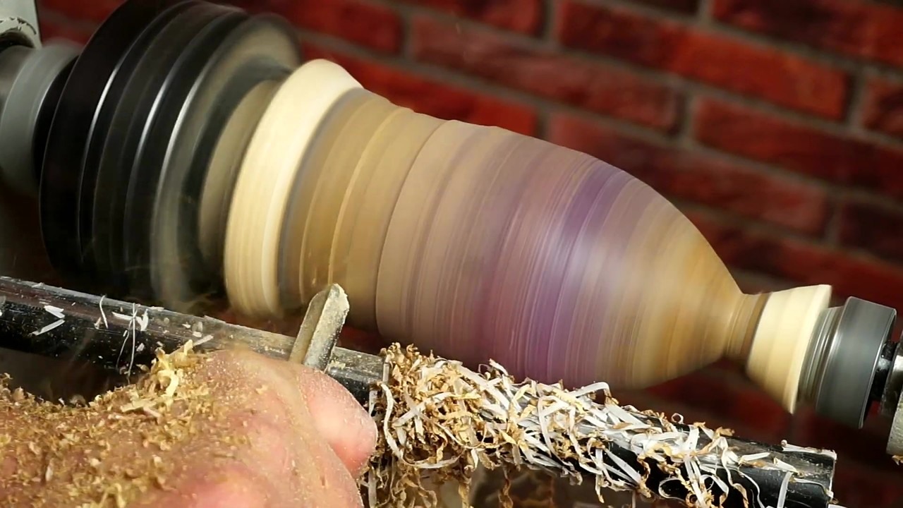 Woodturner shapes wood and purple resin into an egg